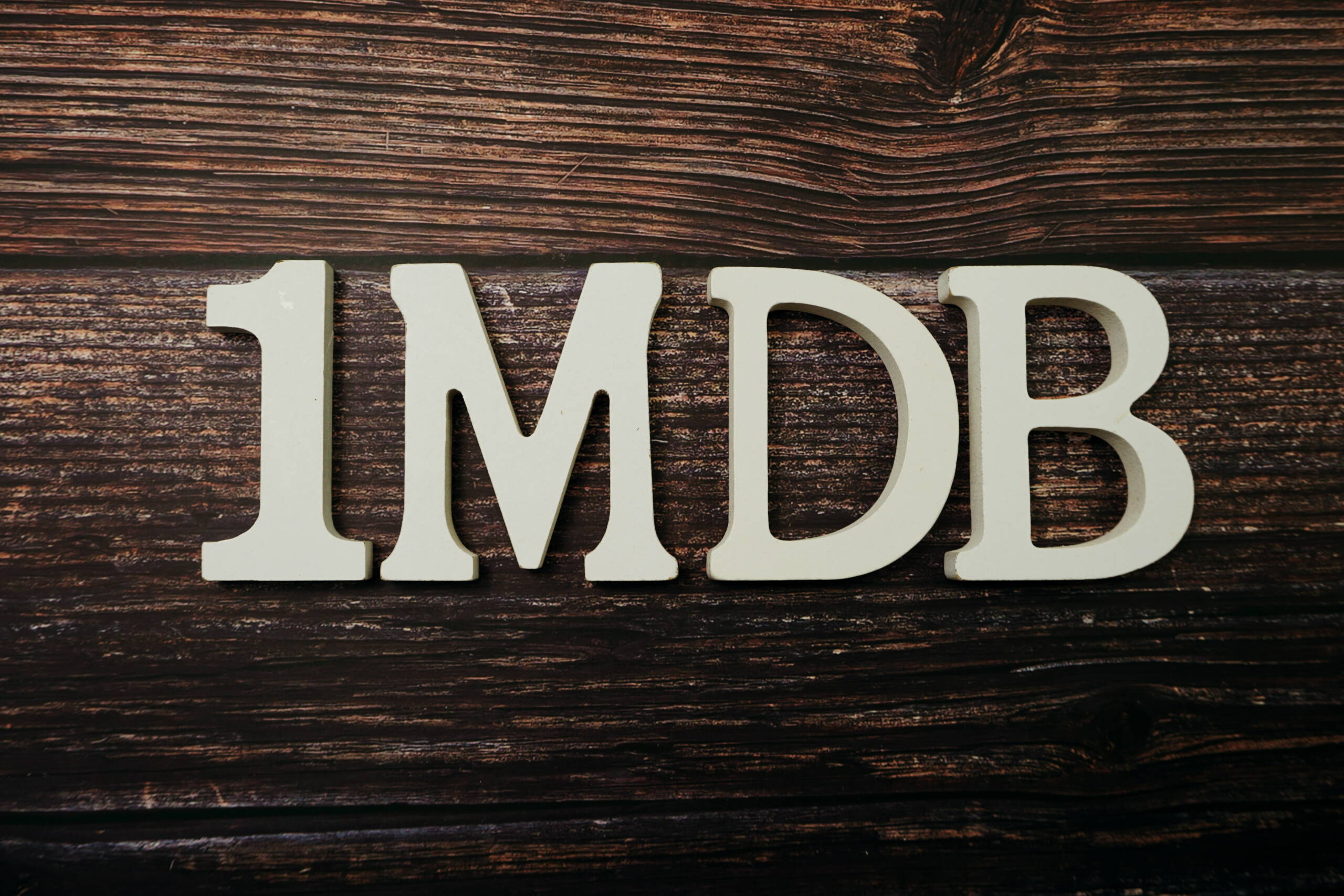 1MDB alphabet letter on wooden background - Cayman Compass
